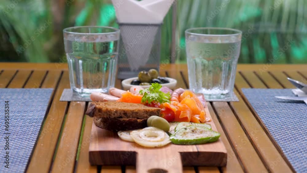 Rustic wooden cutting board displays a variety of cold cuts, including ...