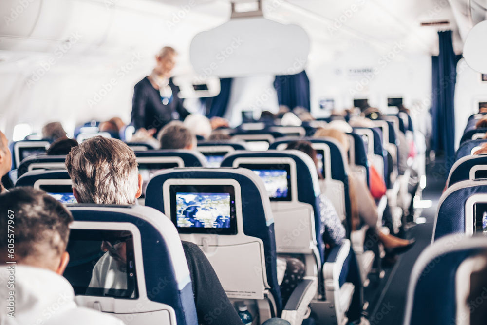 Interior of airplane with passengers on seats and stewardess in uniform ...