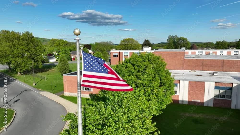 Rotational aerial shot of American flag waving in wind in front of ...