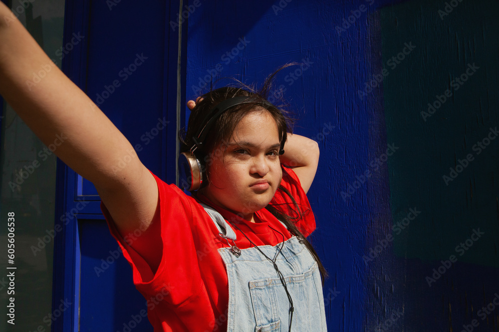 Young curvy woman with Down Syndrome dancing in the sun with headphones ...