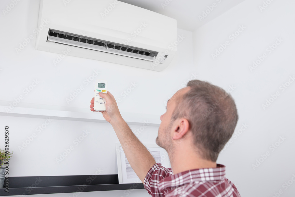 Man holding a modern AC unit remote. Stock Photo | Adobe Stock