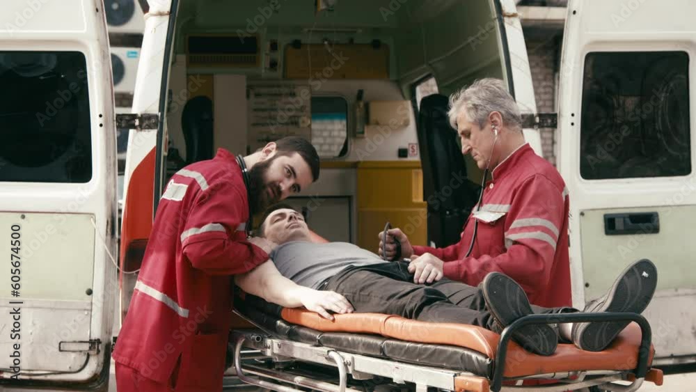 An EMS paramedic team provides medical care to an injured patient. A ...