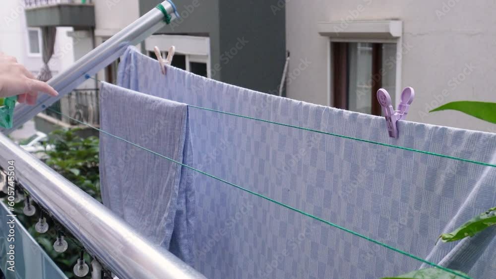 Woman clips clothespins on clothesline for drying laundry. Household ...