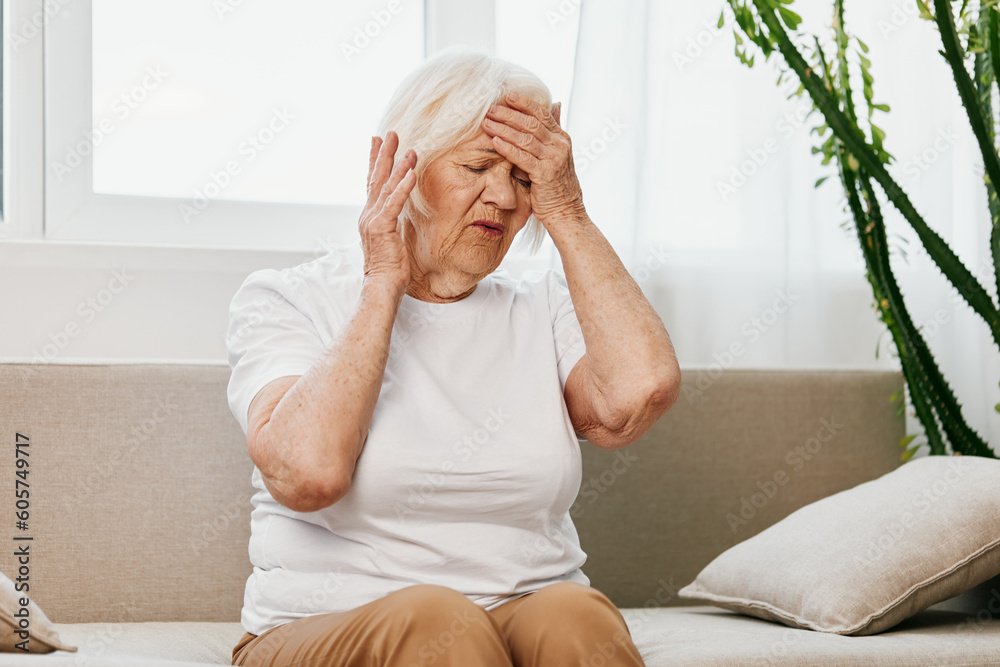 Elderly woman severe pain in the head sitting on the couch, health ...