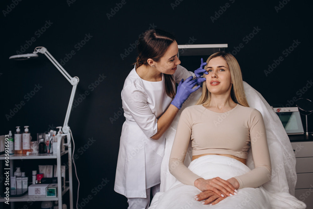 Beautician doctor with botulinum toxin syringe making injection to to ...