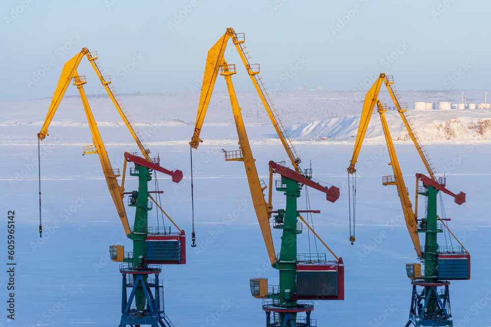 Cargo seaport in the Arctic. Large harbor cranes on a background of ice ...