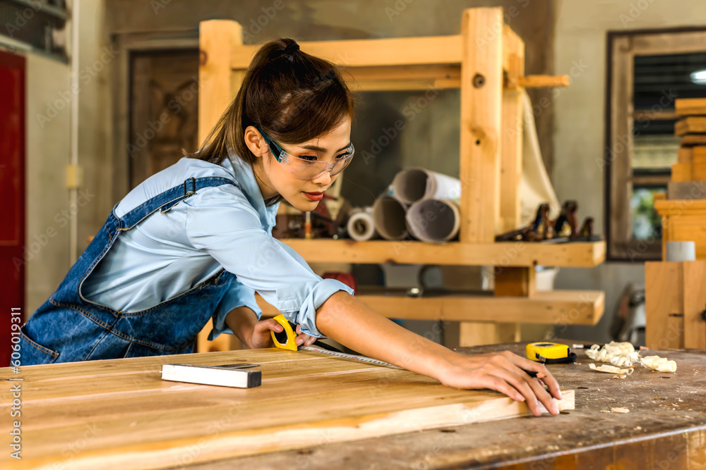 Young Asian woman carpenter working with wood plank in wood work place ...