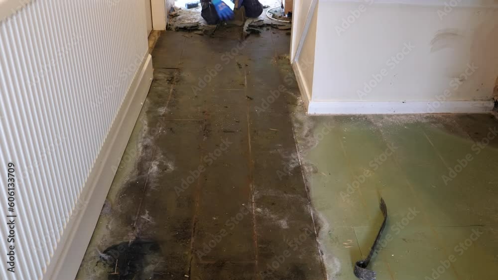 Man, worker wearing safety shoes and gloves removing damaged laminate ...