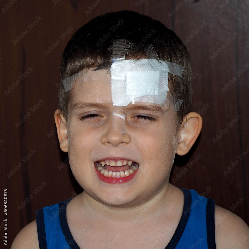 little cute boy with a head injury is crying screaming on a dark ...