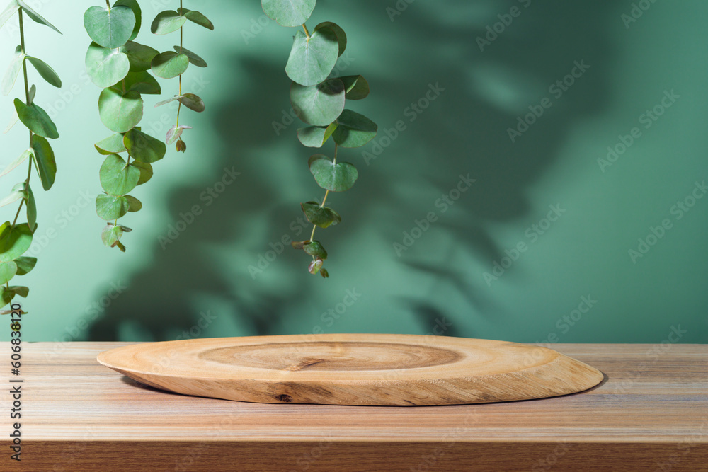 Wooden log board on table with eucalyptus leaves and shadows over green ...