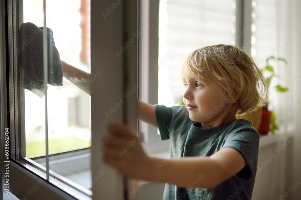 Cute little boy washing a window at home. Child helping parents with ...