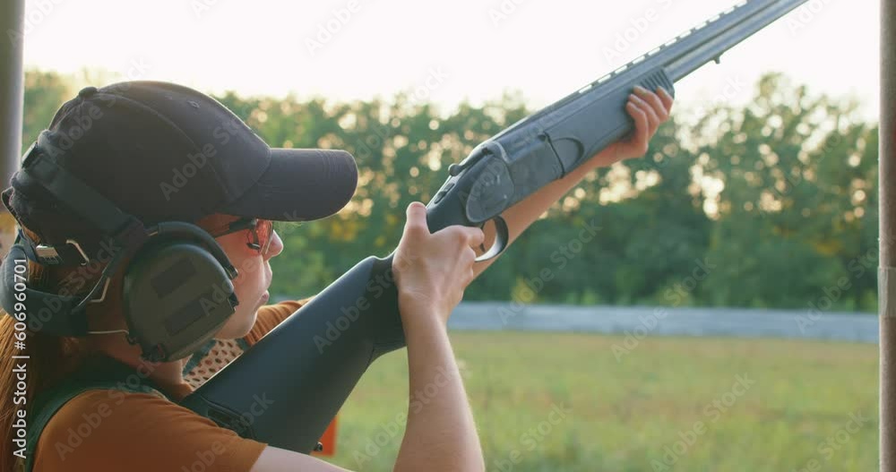 Young man putting a cartridge into his gun, cocking it, aiming and ...
