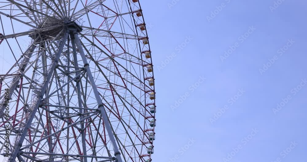A moving ferris wheel at the park behind the blue sky telephoto shot ...
