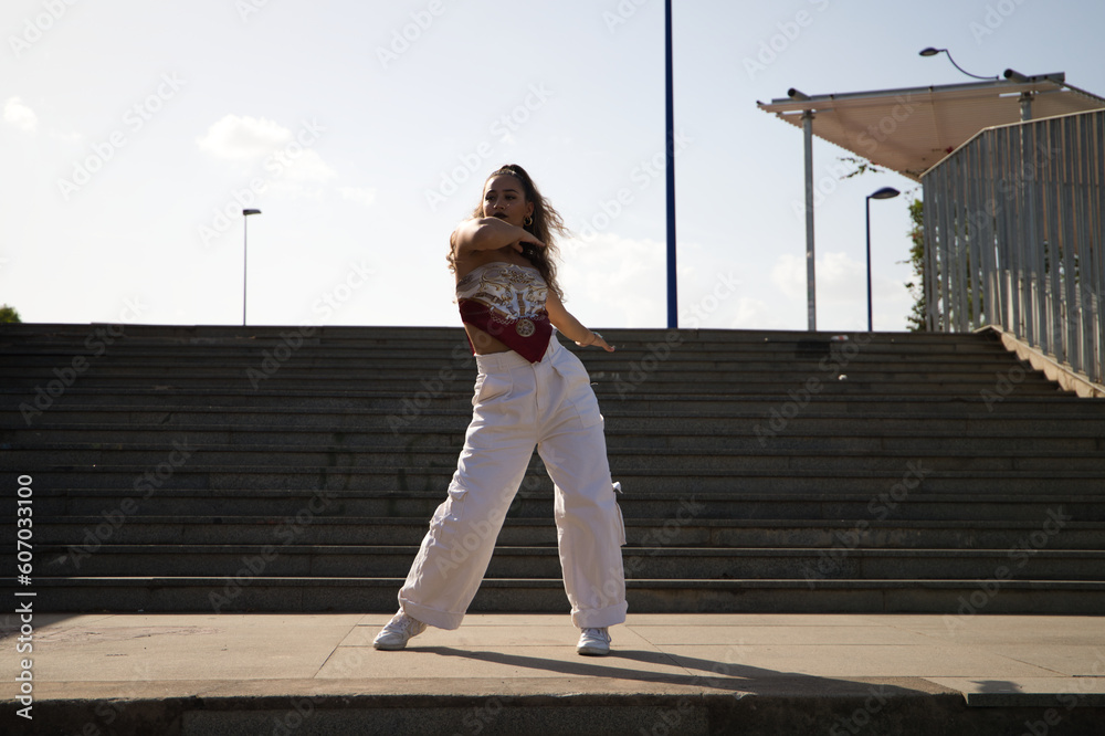 Latin woman, young and beautiful dancing modern dance in the street and ...