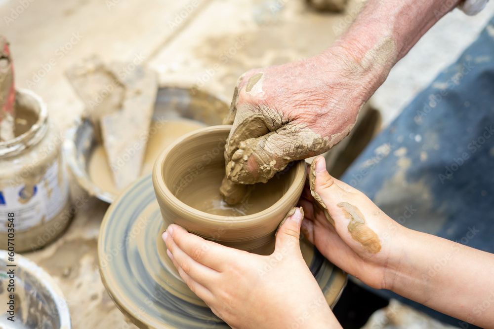 Child learning pottery from an old potter. Passing traditions on trough ...