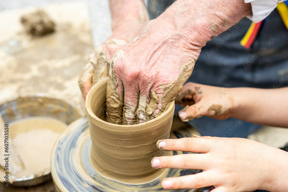 Child learning pottery from an old potter. Passing traditions on trough ...