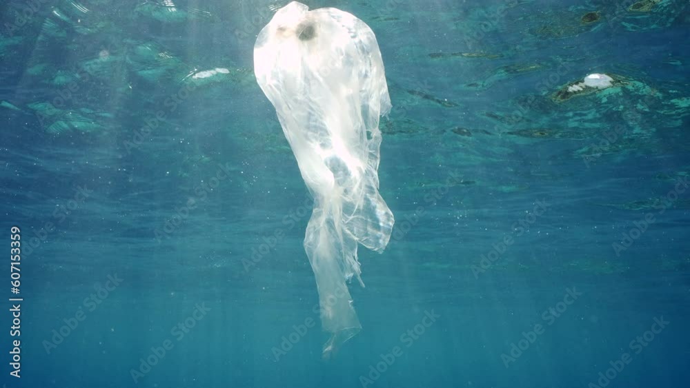 Plastic bag floating in sea on sunny day in sunbeams, Slow motion. An ...