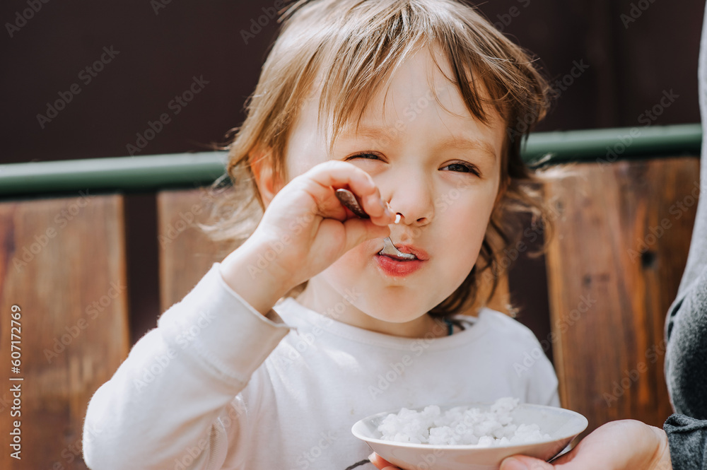 Handsome long-haired little boy of preschool age, happy child eats rice ...