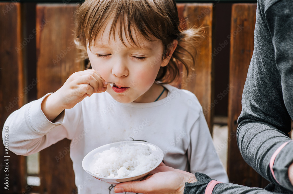 Handsome long-haired little boy of preschool age, happy child eats rice ...
