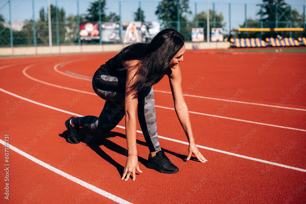 Full body side view of focused young female sprinter in low start ...