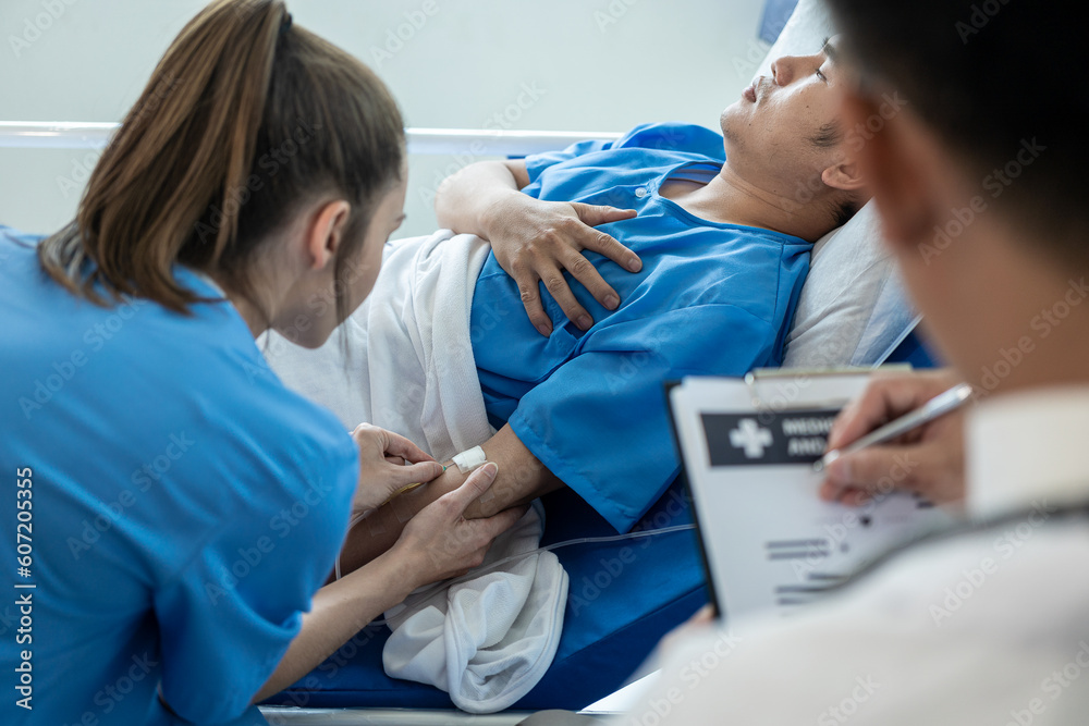 A female doctor and two male doctors treat a young male patient in bed ...