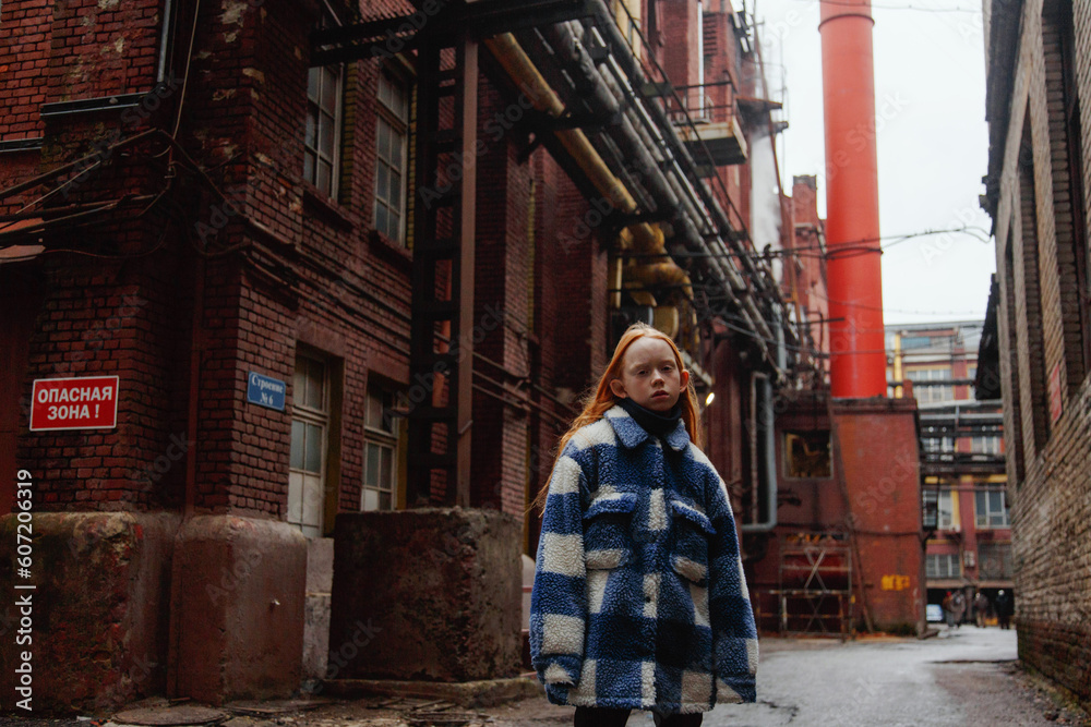Girl in blue and white checkered coat standing in front of brown ...