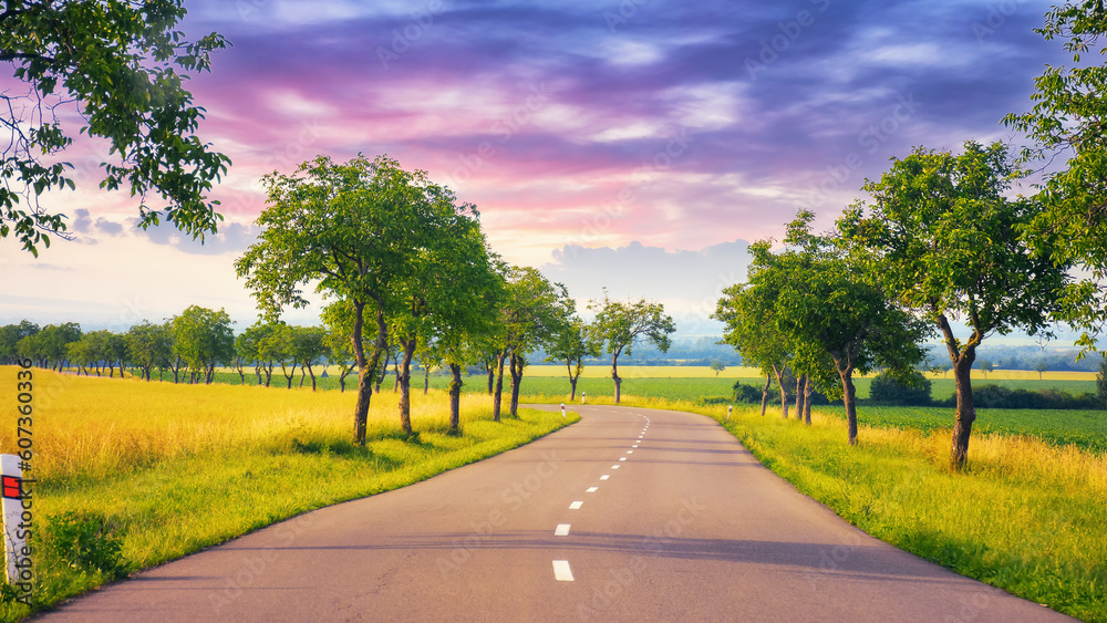 as the sun sets, the road leads through a beautiful countryside ...