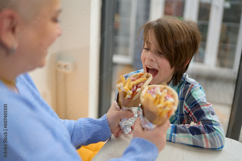 Foto de Hungry little boy taking a bite of a gyros wrap sandwich in a ...