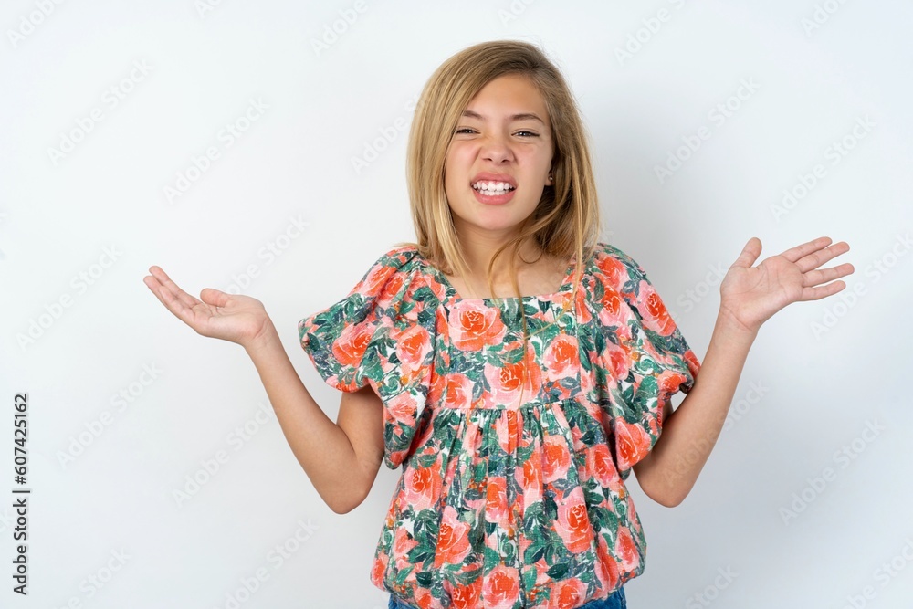 Indignant beautiful teen girl wearing flowered blouse over white studio ...