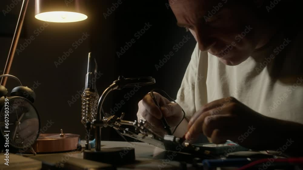A person using a multimeter studies a microcircuit looking for an open ...