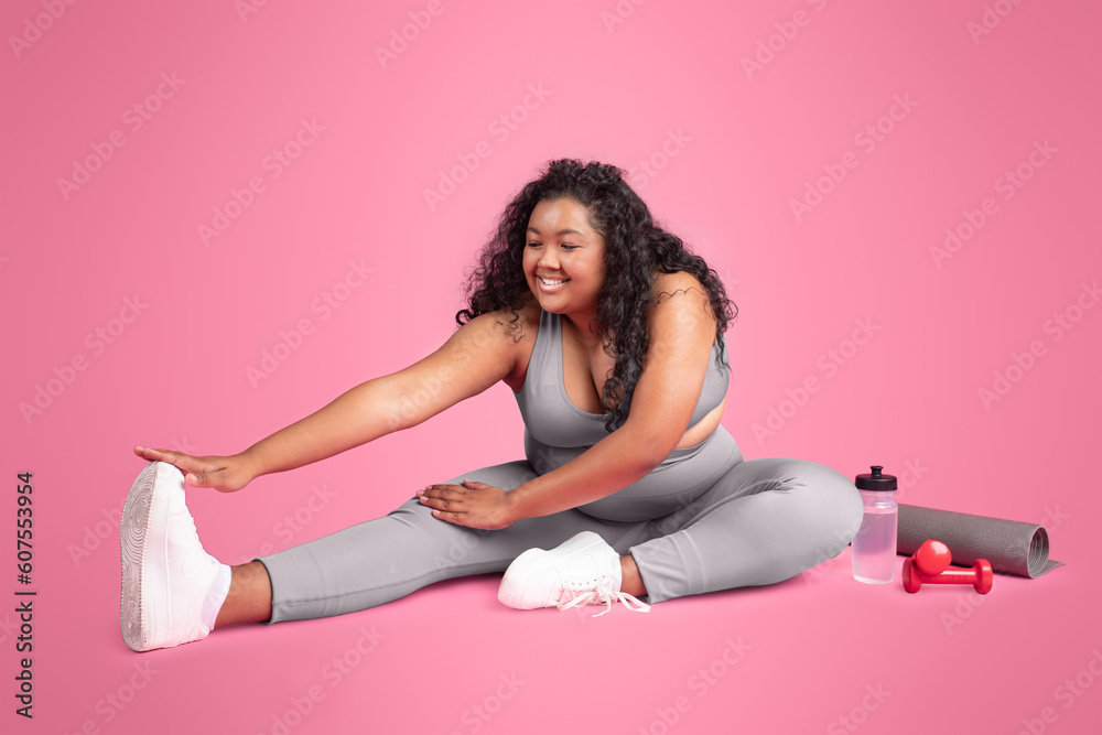 Happy black plus size woman stretching her legs, exercising during ...