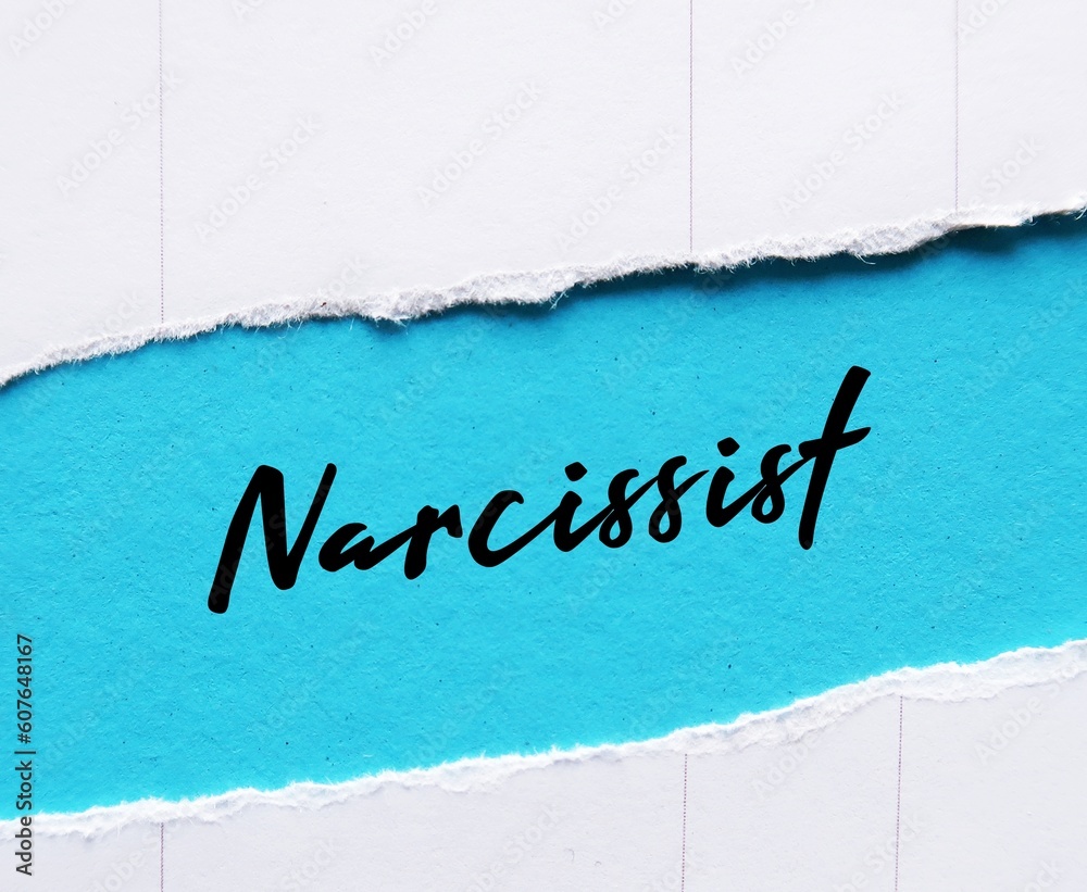 Torn paper on blue backgroundl with handwritten text NARCISSIST, self ...