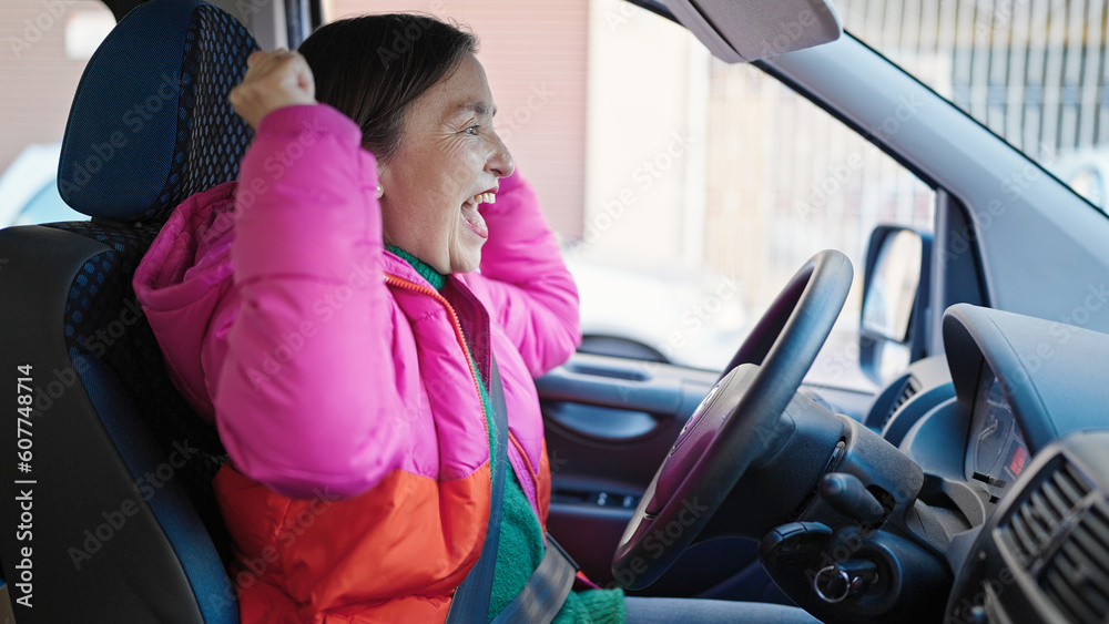 Mature hispanic woman with grey hair driving car with winner expression ...