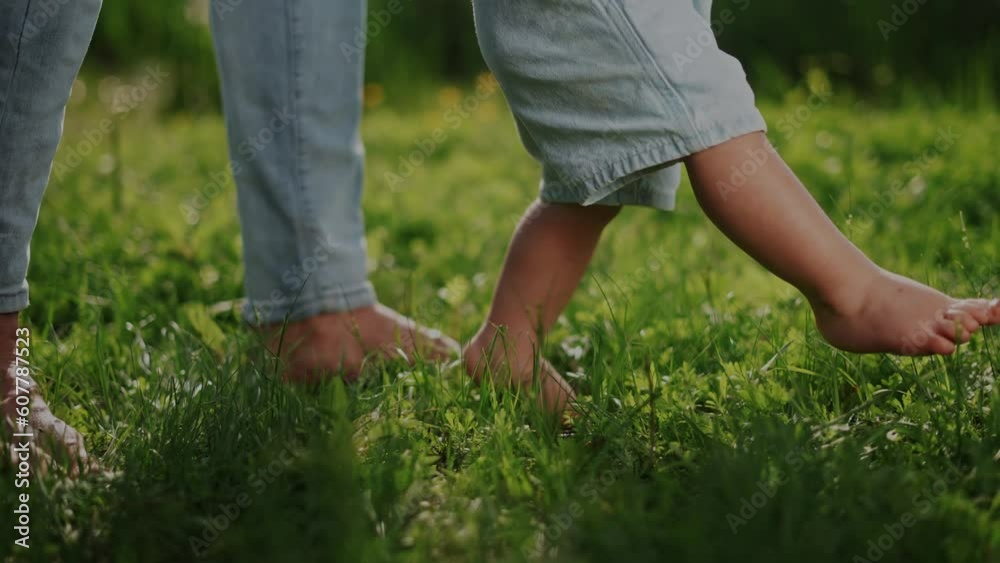 happy family. baby takes first steps a in grass. father walk with son ...