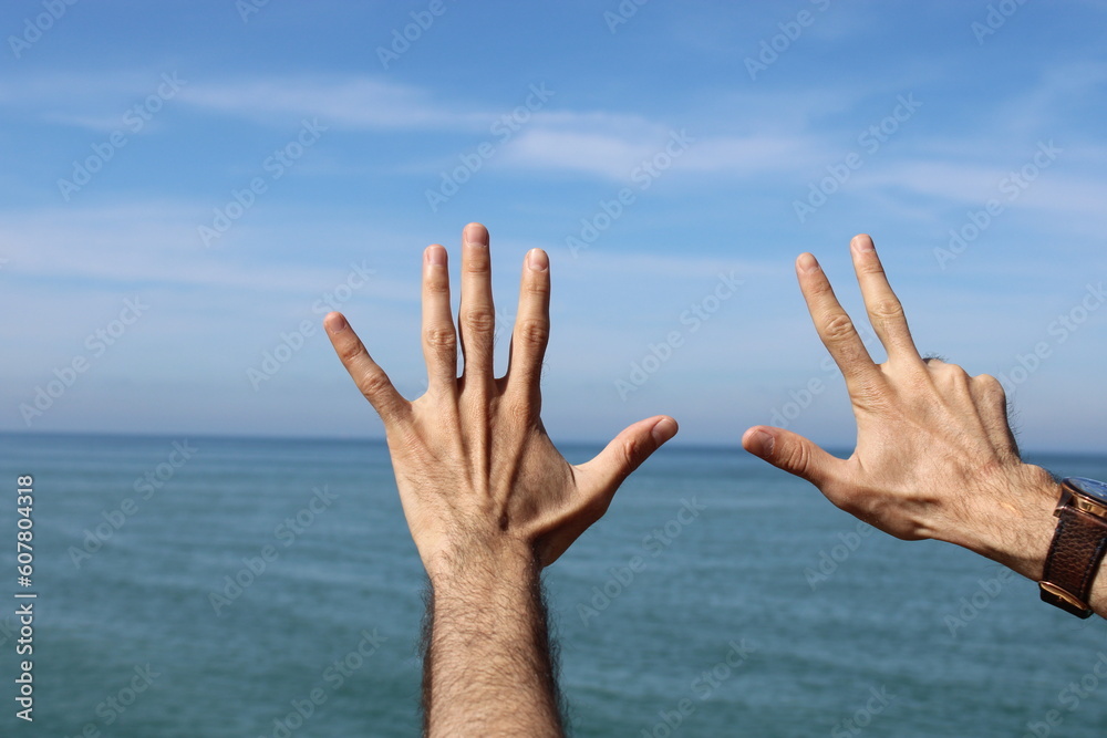 Hand doing,showing number eight gesture symbol on blue summer sky ...