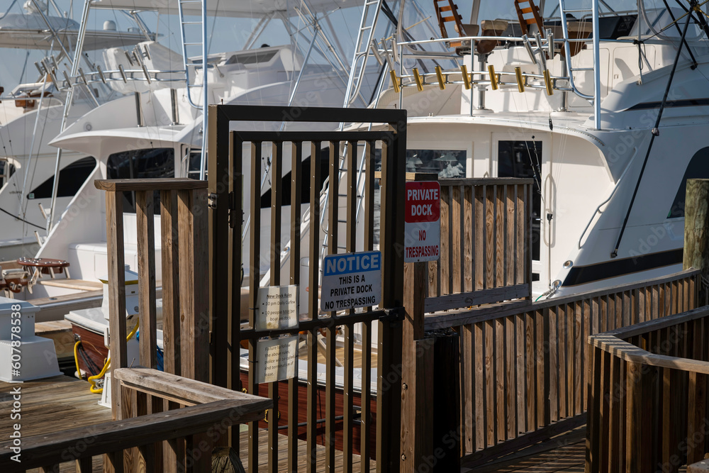 Gate entrance to a private marina dock with fishing boats, with signs ...