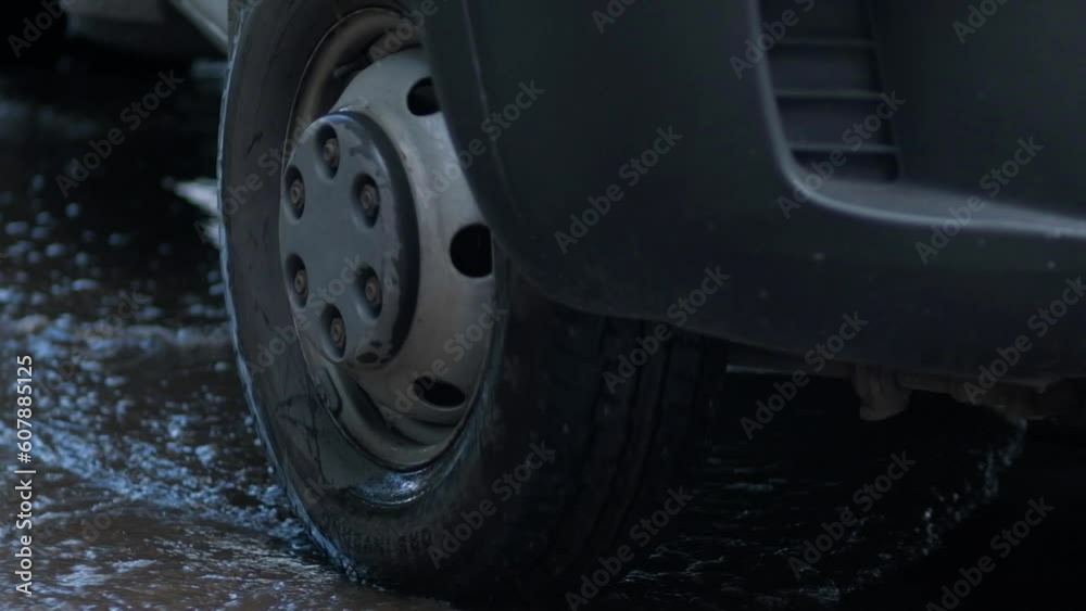 The wheel of the car is driving through a huge puddle on the road after ...