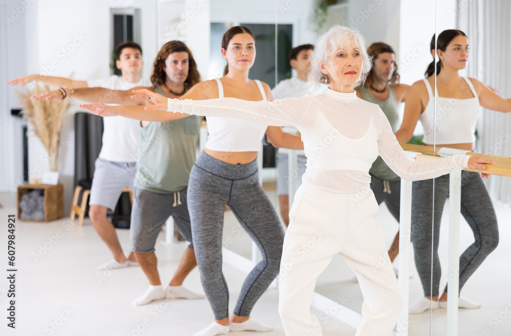 Group of people of different ages practice ballet moves in classical ...