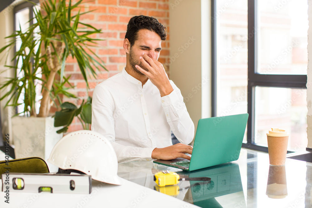 young hispanic man feeling disgusted, holding nose to avoid smelling a ...