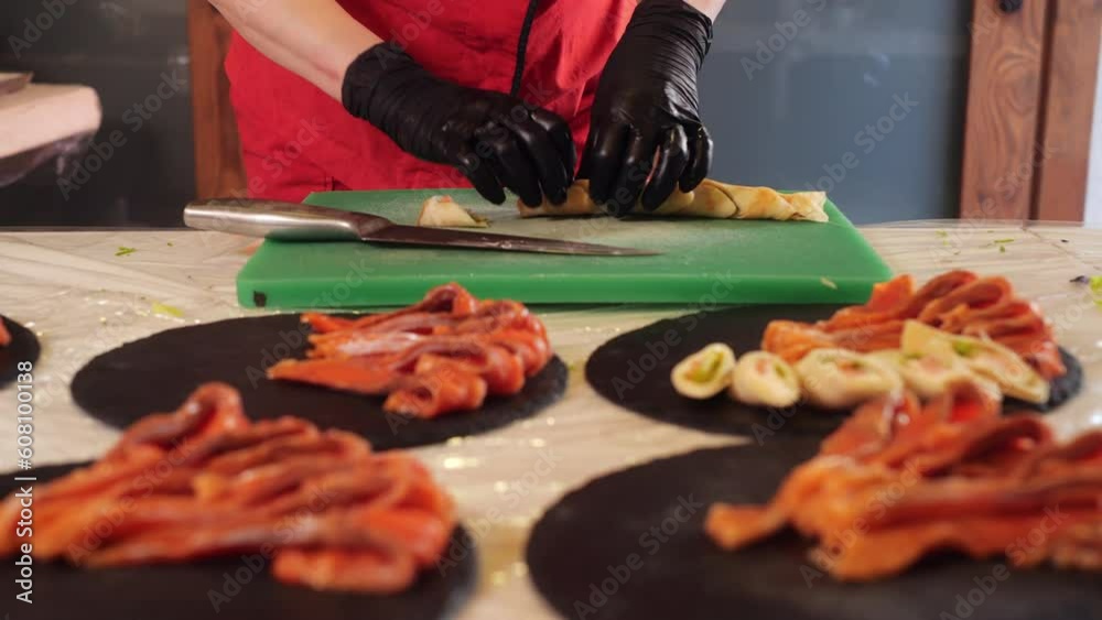 Chef cook woman black gloves cooking and serving dishes with snacks in ...