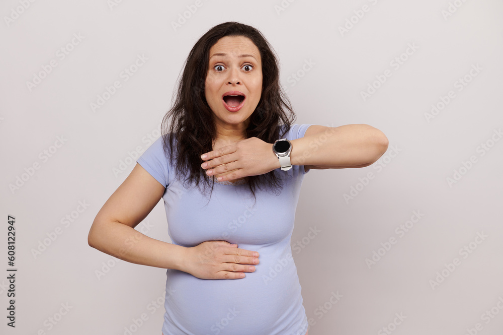 Emotional studio portrait of excited pregnant woman touching her belly ...