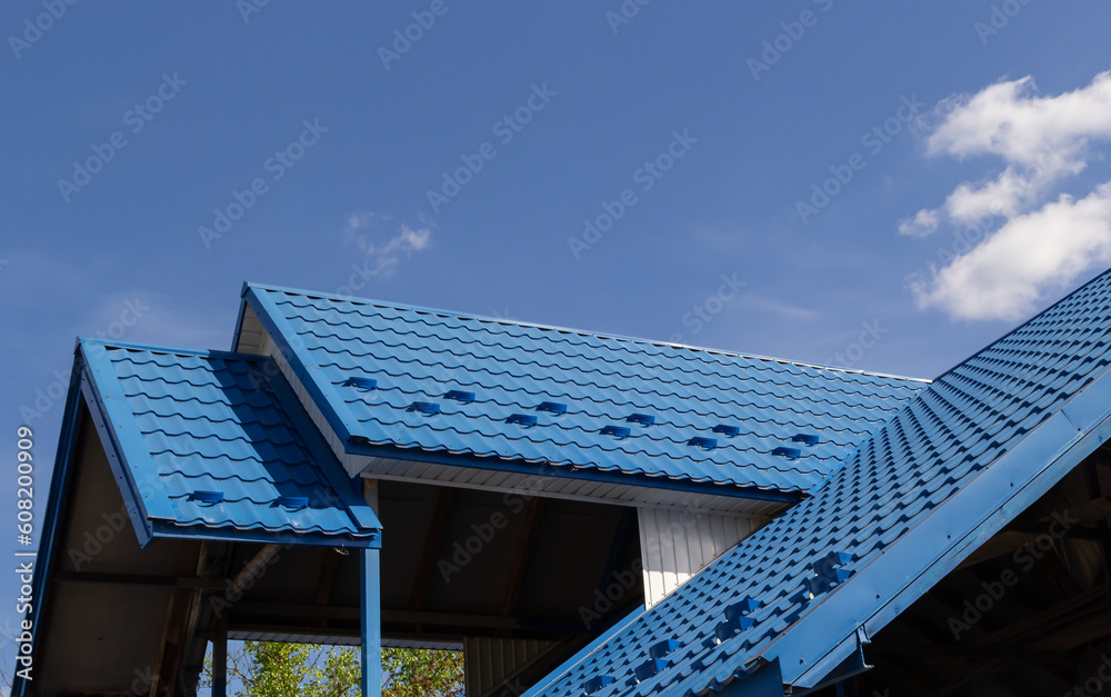The roof of a house covered with sheets of blue metal tiles against the ...