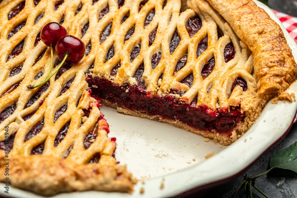 One piece on a plate and the whole homemade cherry pie on a light ...