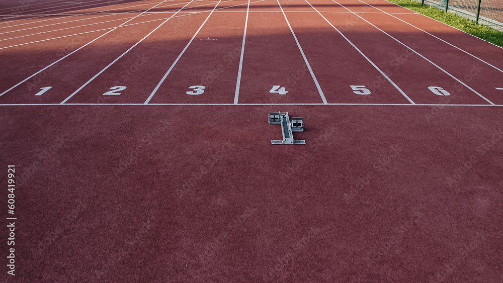 Starting block and starting line of the red tartan athletic track with ...