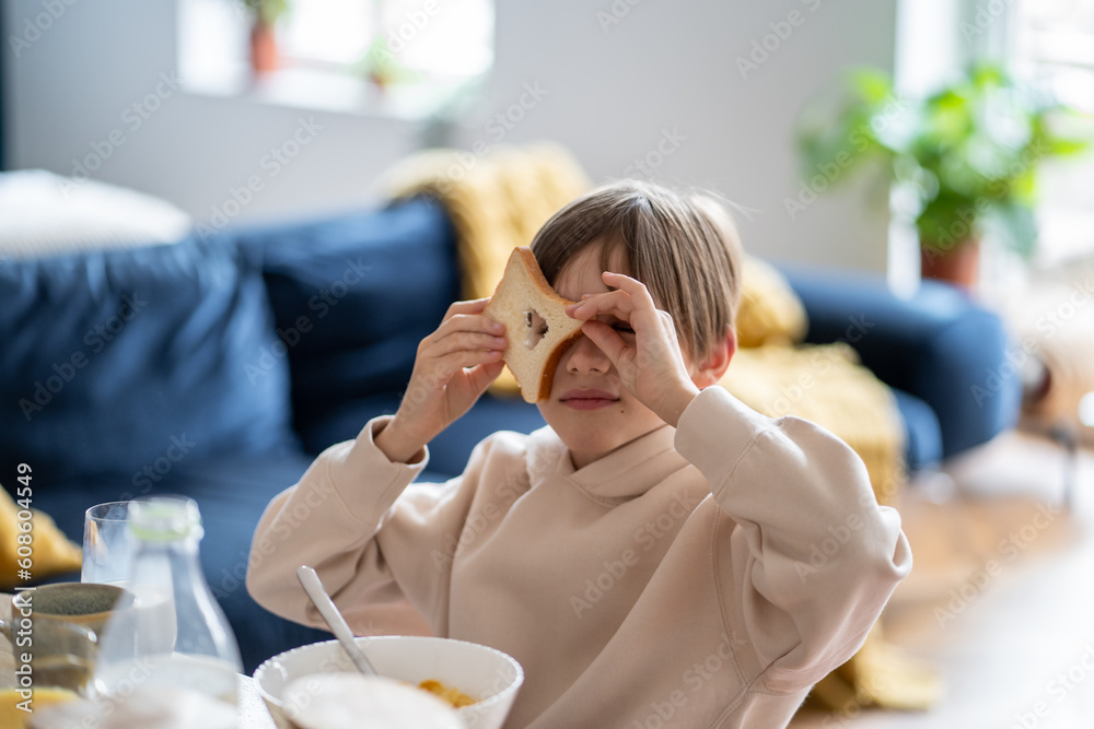 Boy child playing with slice of bread while sitting at kitchen table ...