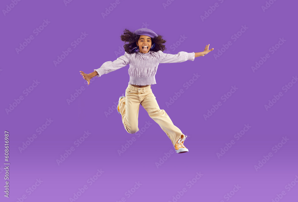 Hooray. Happy joyful kid girl in comfortable trendy wear jumping high ...