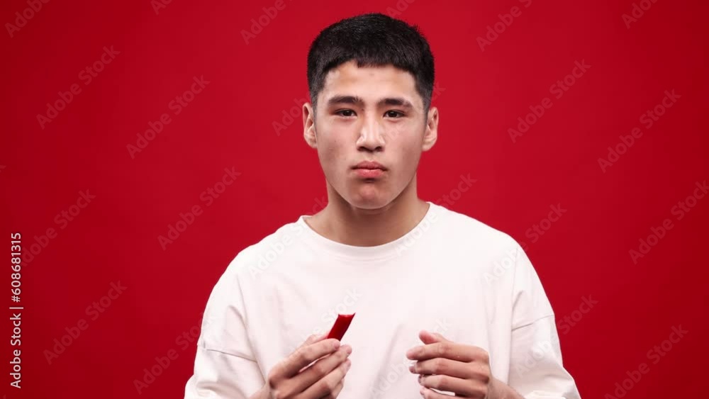 Burning mouth. Young asian man eating red hot chilli peppers against ...
