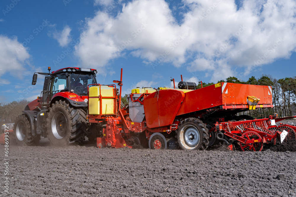 Roter Trecker mit roter moderner Kartoffellegemaschine auf einen Feld ...