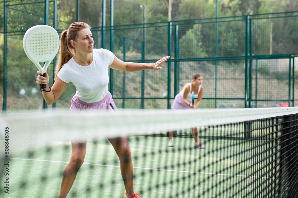 Female player playing padel in a padel court outdoor behind the net ...