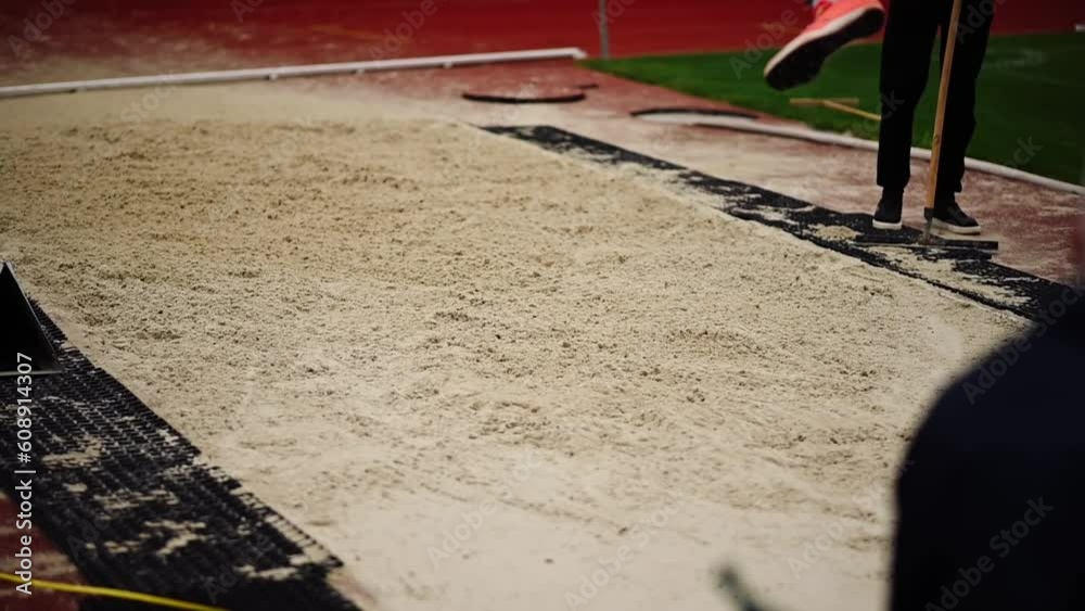 An athlete performs a long jump with a landing in a sandbox. Athletics ...
